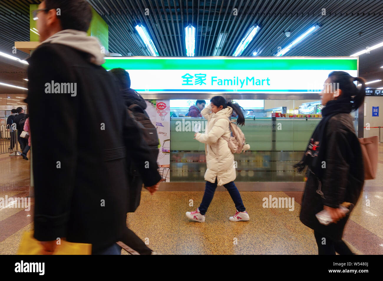 Passengers walk past the convenience store of FamilyMart at the Jing'an ...