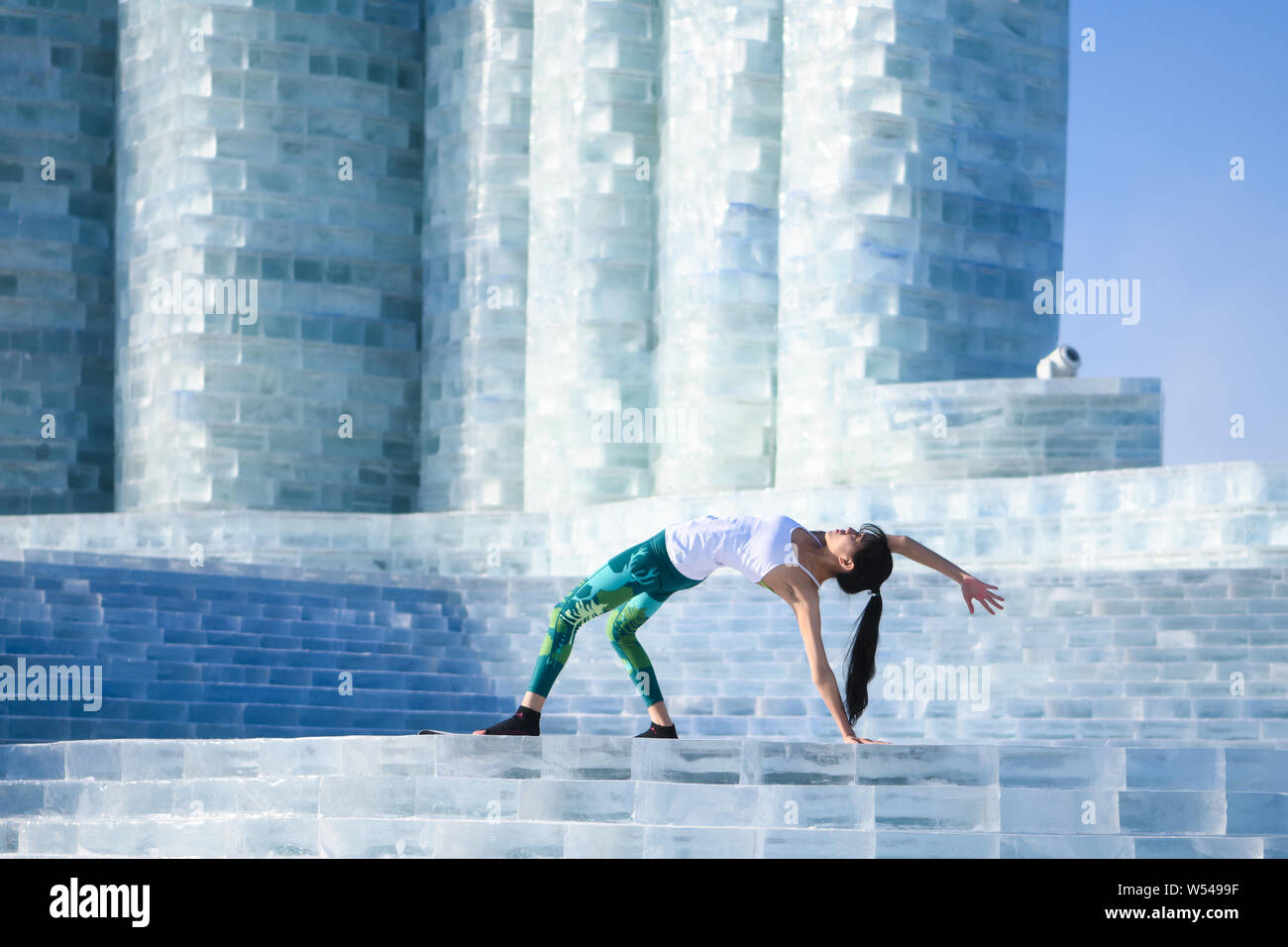 A Chinese yoga enthusiast performs yoga in front of ice sculptures ...