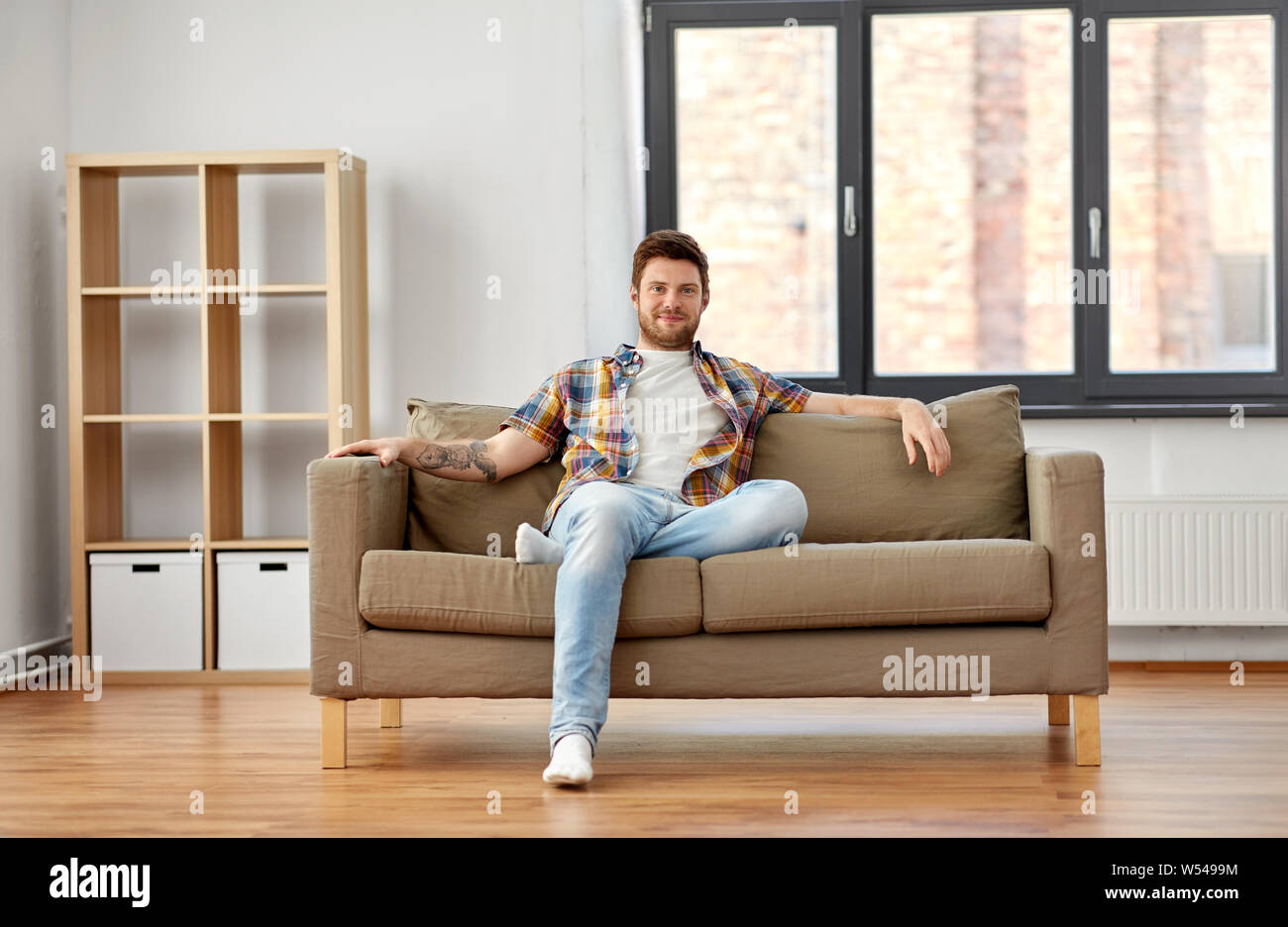 happy man sitting on sofa at new home Stock Photo - Alamy