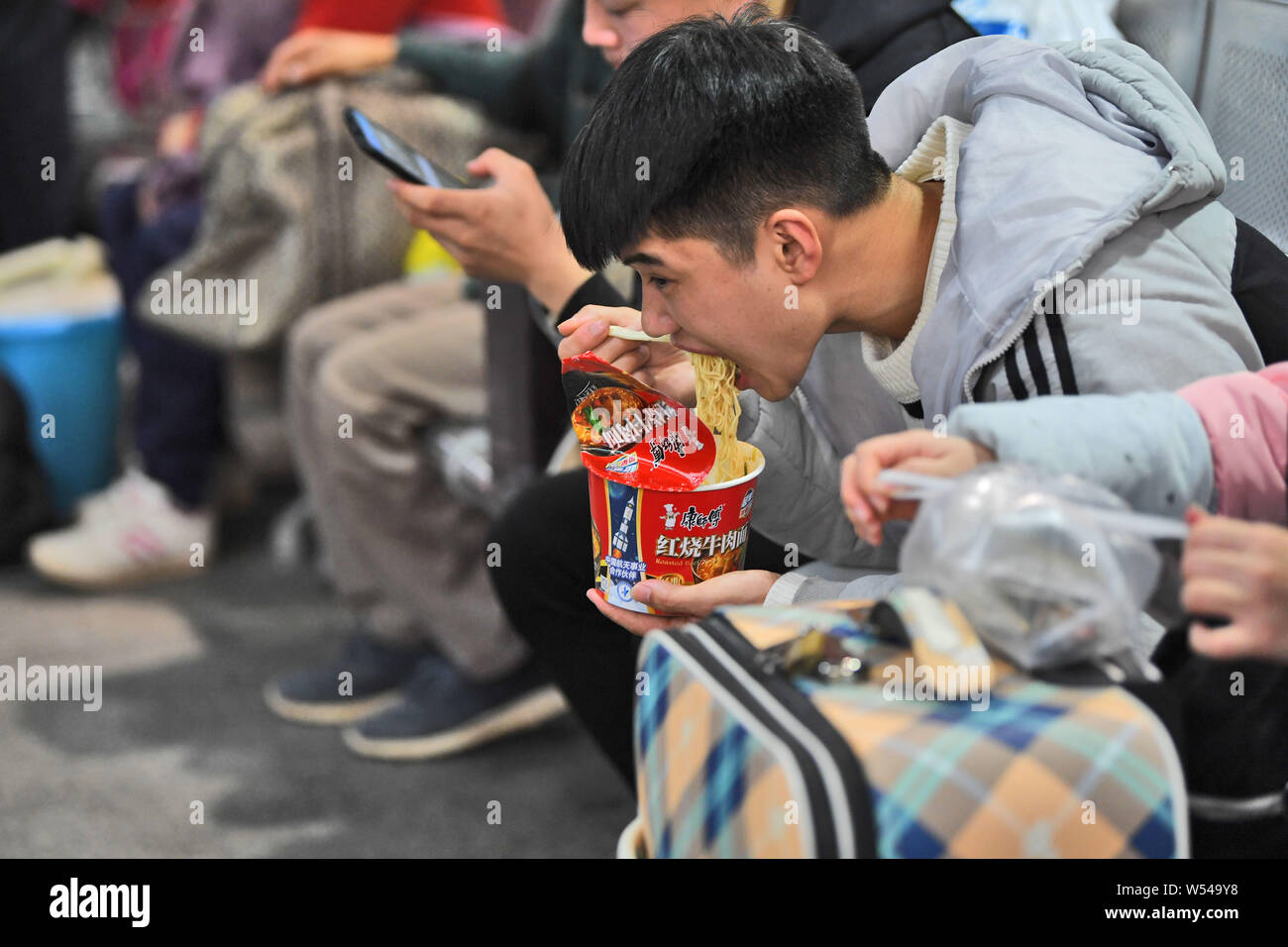 A passenger eats instant noodle as he waits for the train at the ...