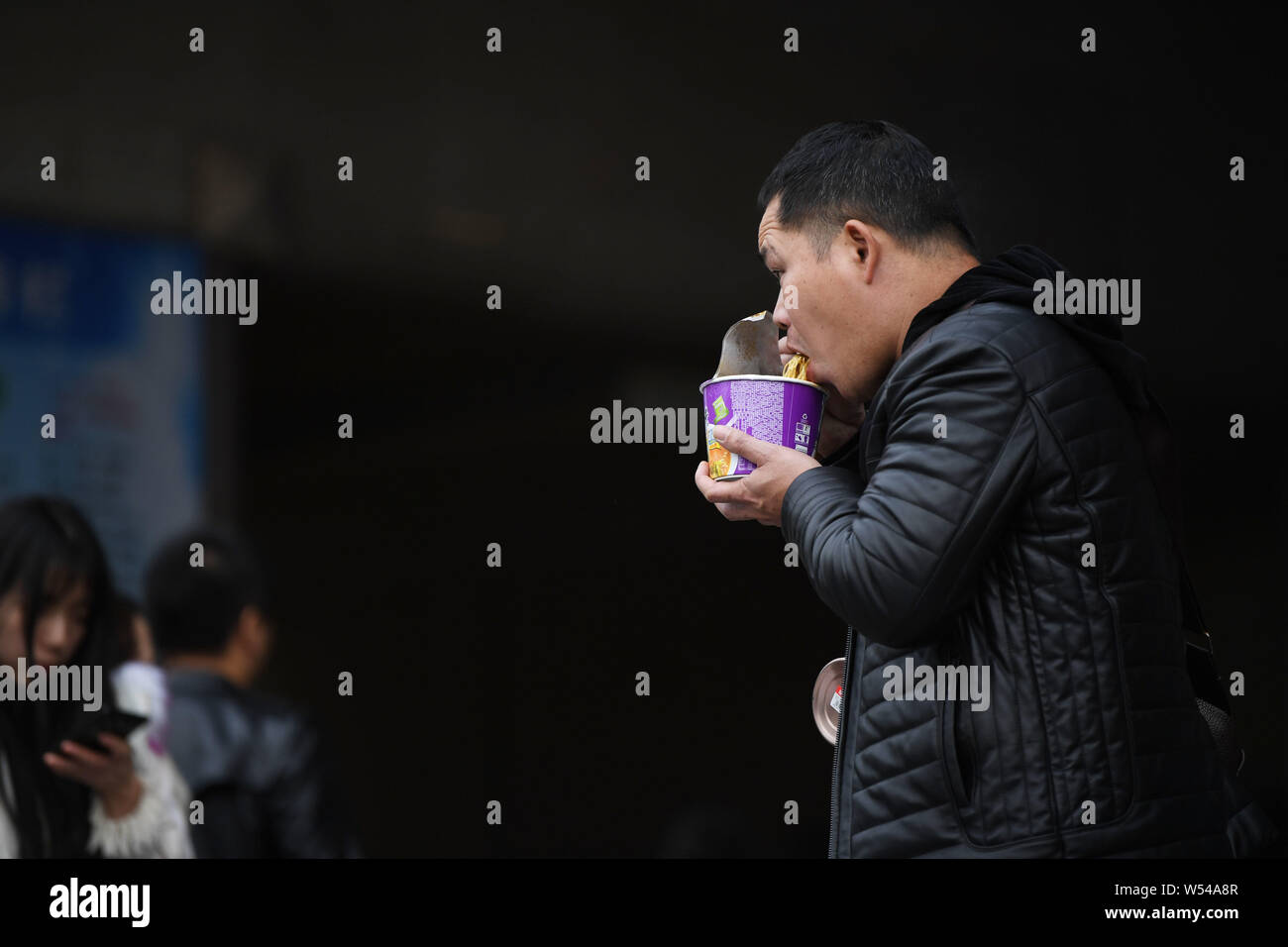 A passenger eats instant noodle as he waits for the train at the ...