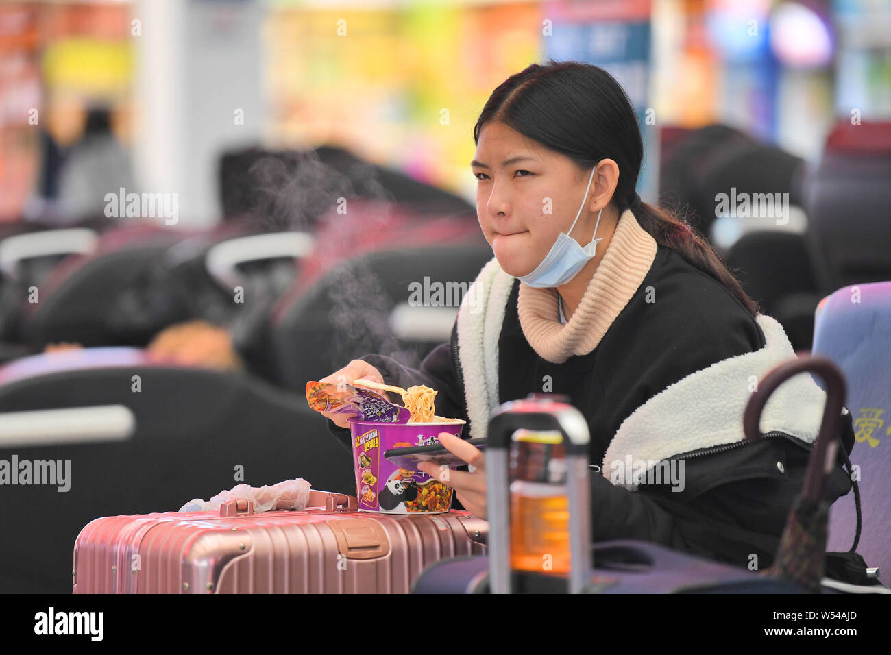 A passenger eats instant noodle as she waits for the train at the ...
