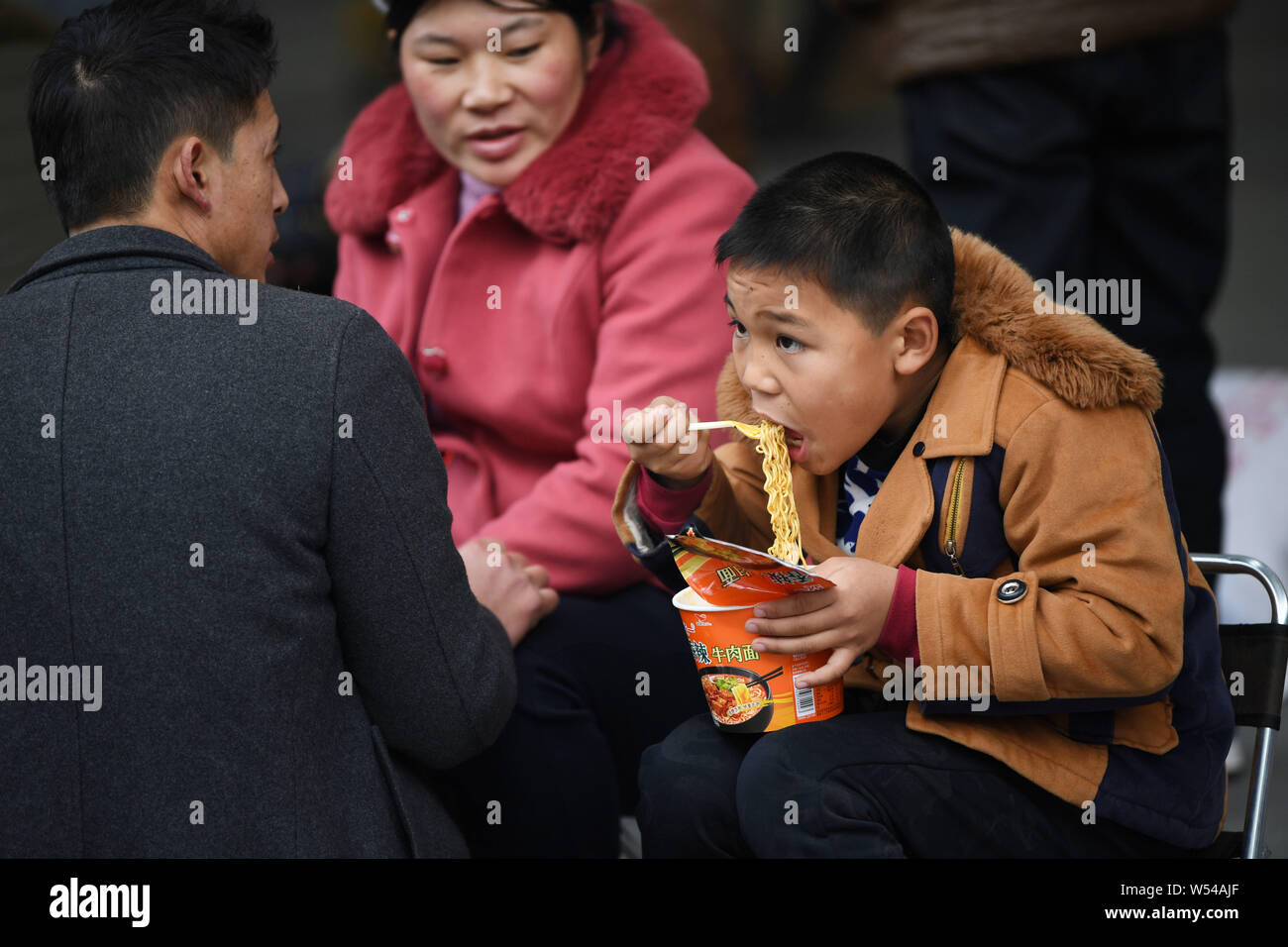 A passenger eats instant noodle as he waits for the train at the ...