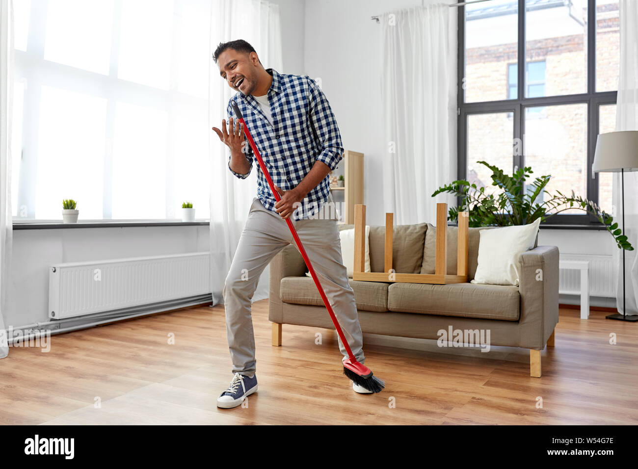man with broom cleaning and singing at home Stock Photo - Alamy