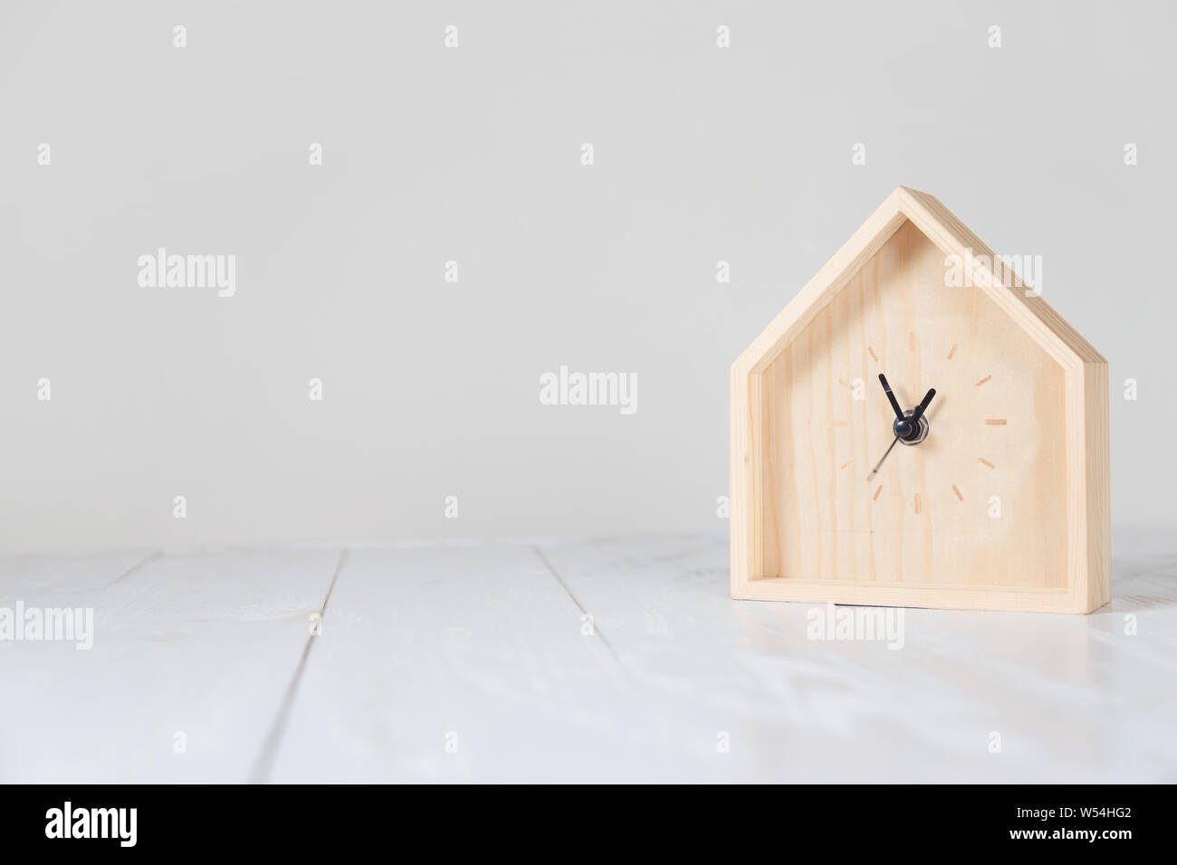 Wooden table clock in the shape of a house on white wooden shelf Stock ...