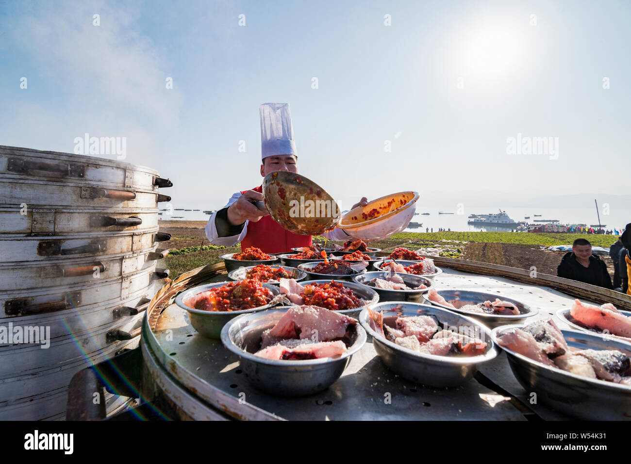 A Chinese chef prepares free fish dishes to tourists during the fourth ...