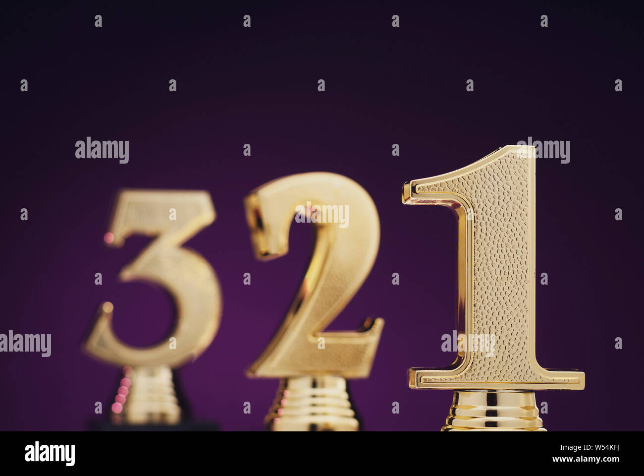 Close up view of three separate slightly blurry golden number trophies ...