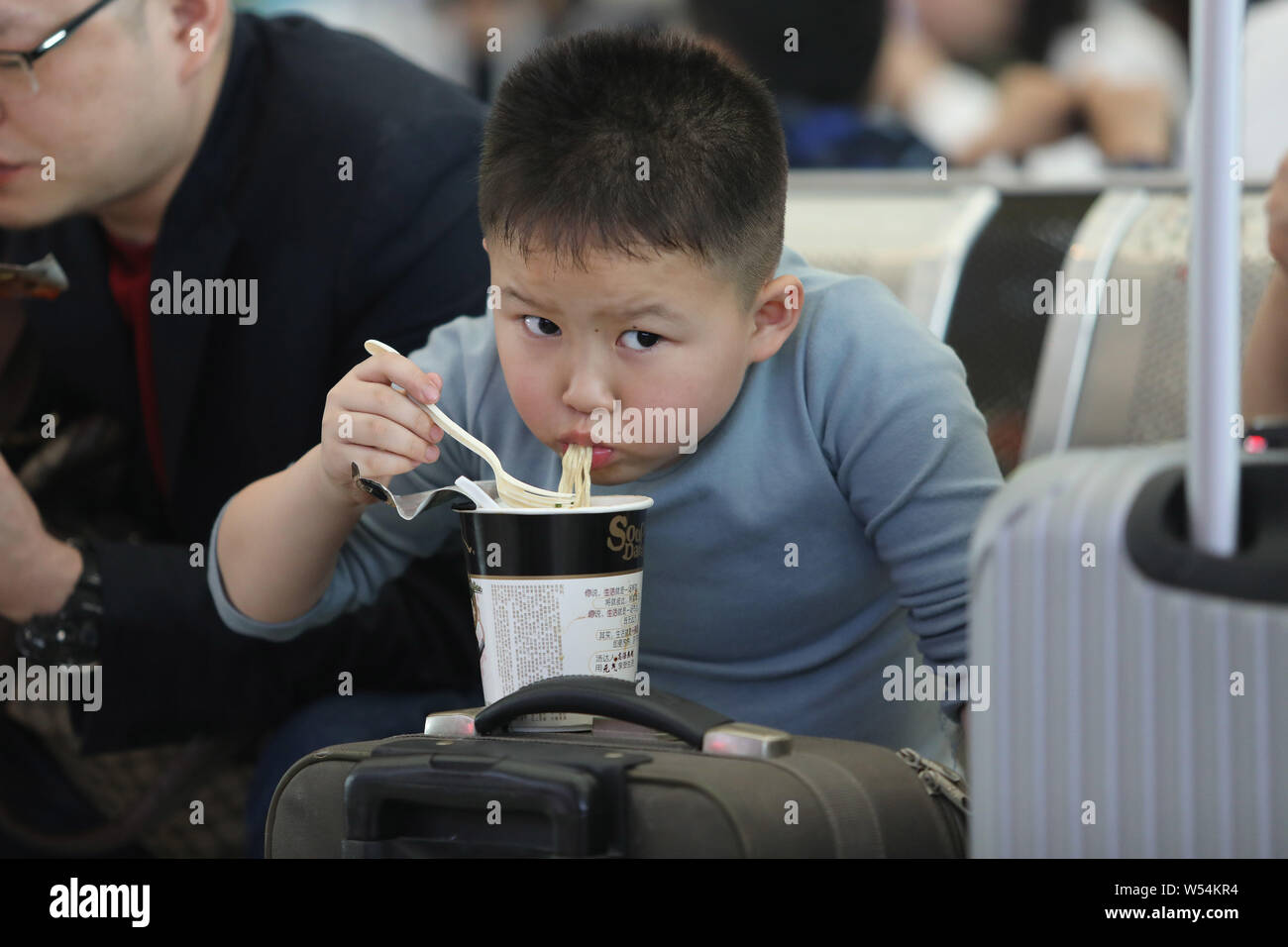 A passenger eats instant noodle as he waits for his train during the ...
