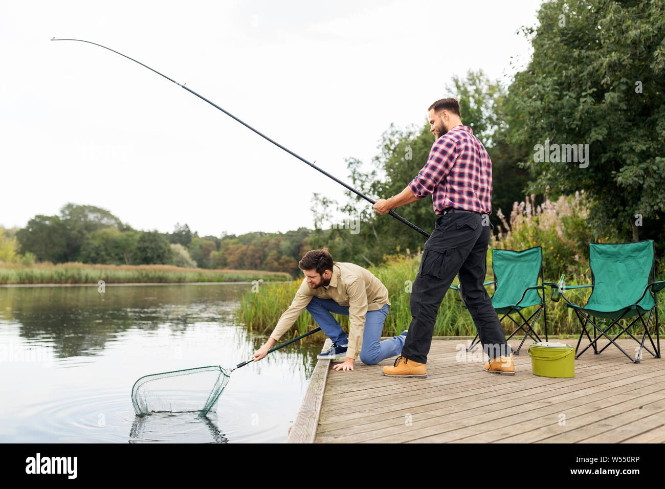 male friends with net and fishing rods on lake Stock Photo - Alamy