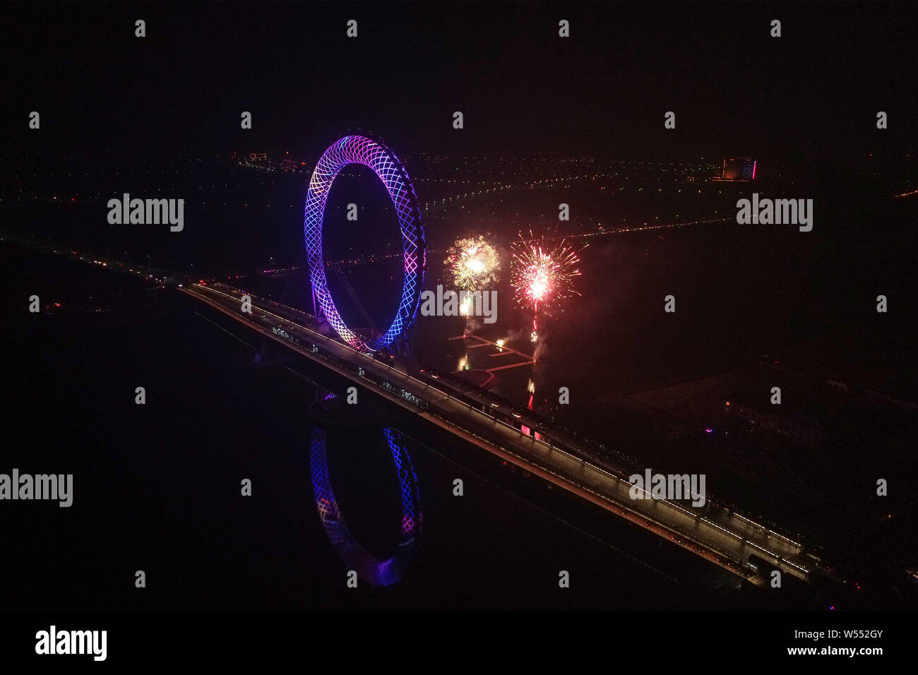Fireworks explode beside the illuminated Bailang River Bridge Ferris Wheel, the world's largest ...