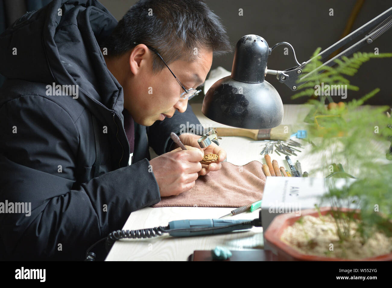 Chinese artist Li Yanjun works on a micro sculpture on a peach pit at ...