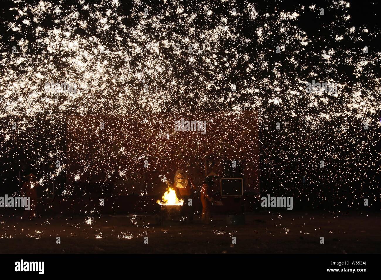 Performers spray molten iron water to create sparks into the sky during ...