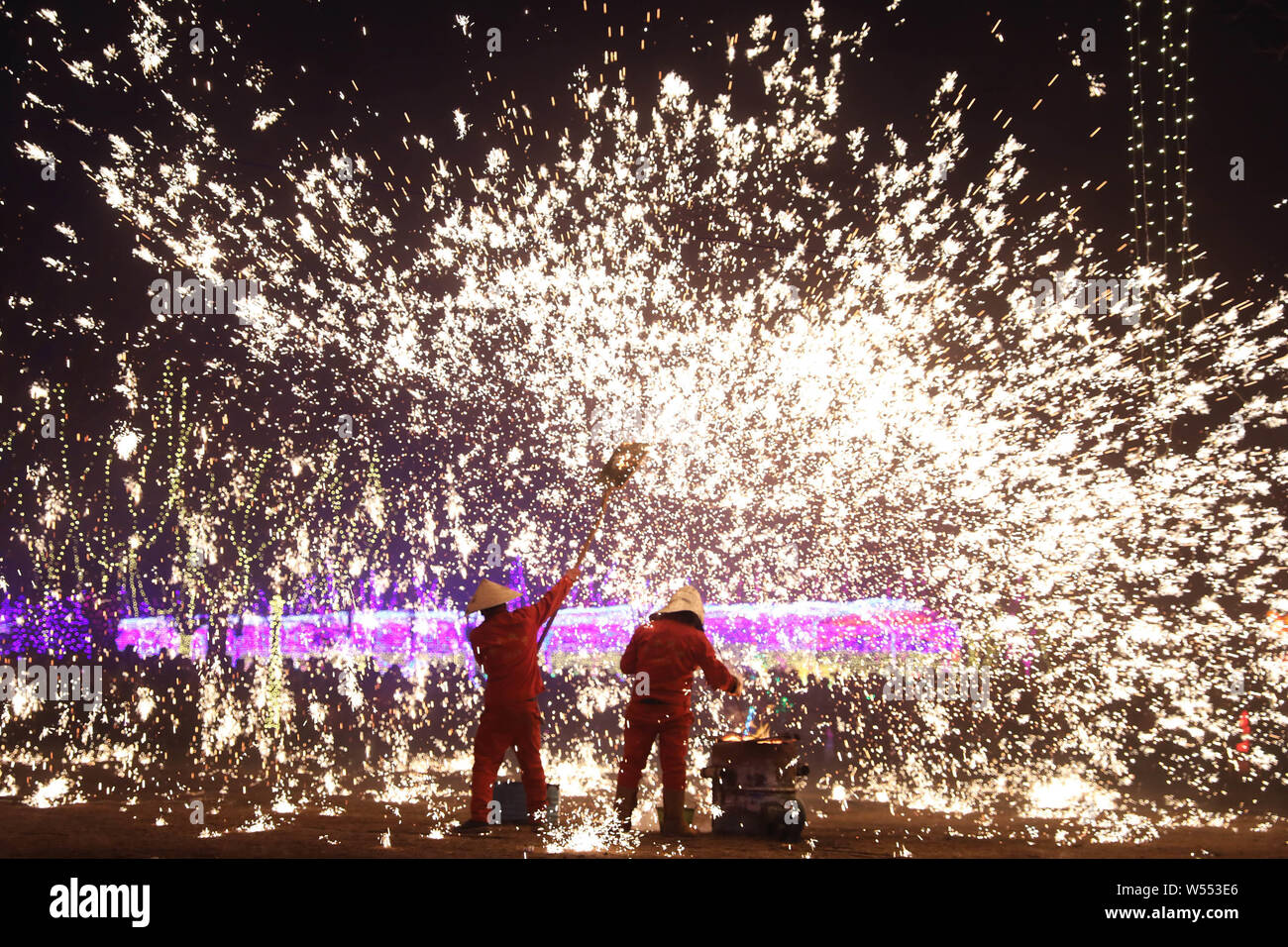 Performers spray molten iron water to create sparks into the sky during ...