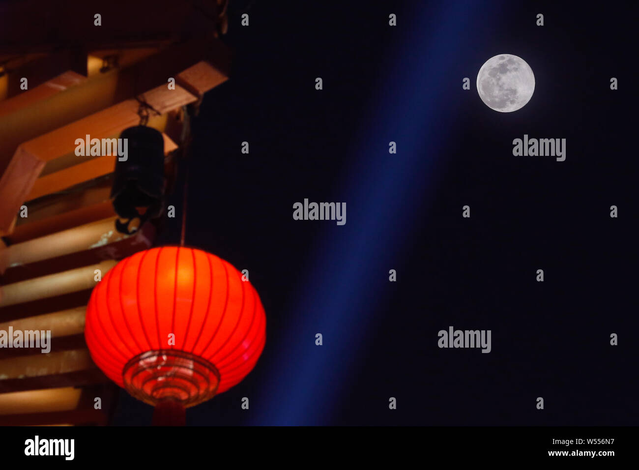 The full moon is seen in the sky over a traditional Chinese building ...