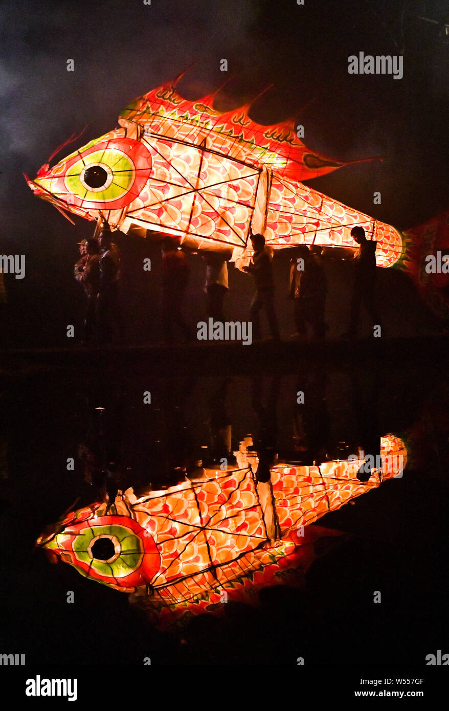 Villagers holding fish-shaped lanterns parade during a local festival ...