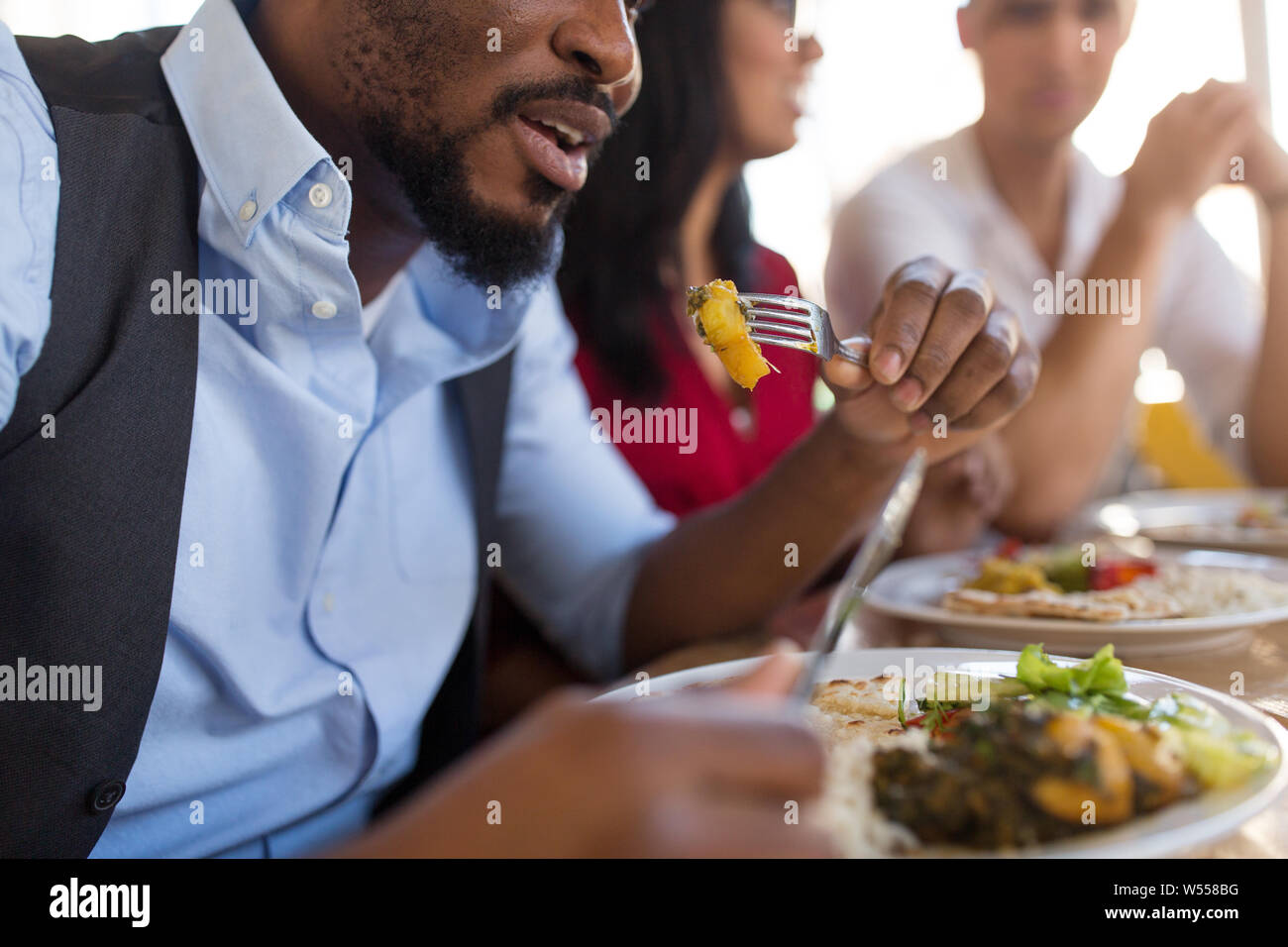 african man eating with friends at restaurant Stock Photo - Alamy