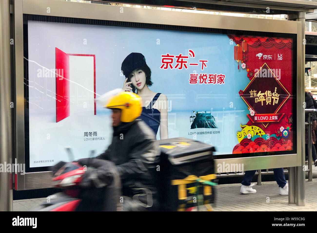 --FILE--A food delivery courier rides past an advertisement for Chinese ...