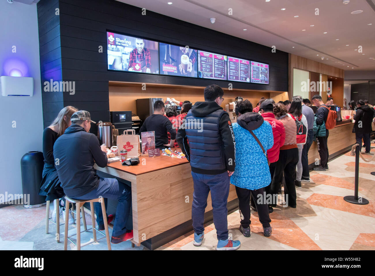 Consumers wait in line to buy coffee from Tim Hortons' first store in ...