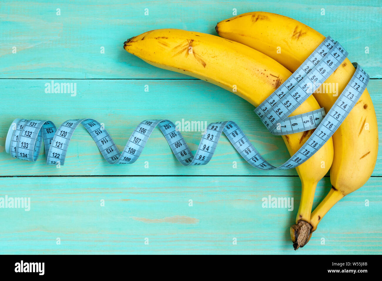 Closeup view of bananas and measuring tape on wooden background.Healthy ...