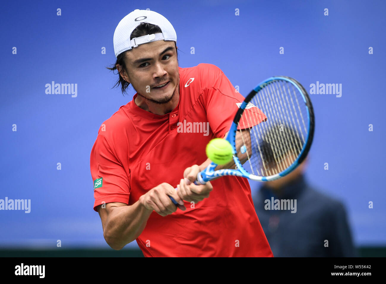 Taro Daniel of Japan returns a shot to Zhang Ze of China in their group ...