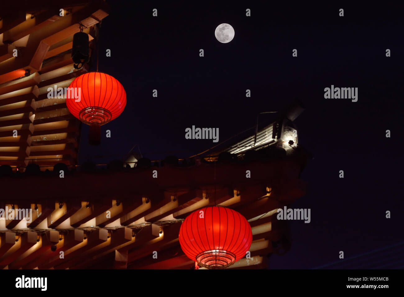 The full moon is seen in the sky over a traditional Chinese building ...