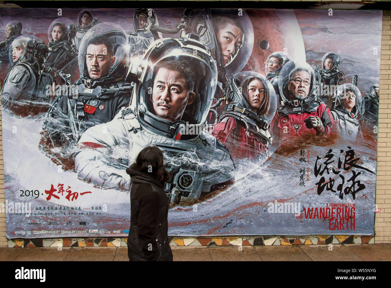 A pedestrian walks past a poster of the movie "The Wandering Earth ...