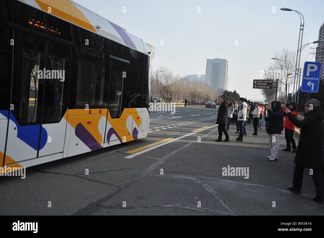 Local residents crowd a newly-developed smart electric train on a road ...