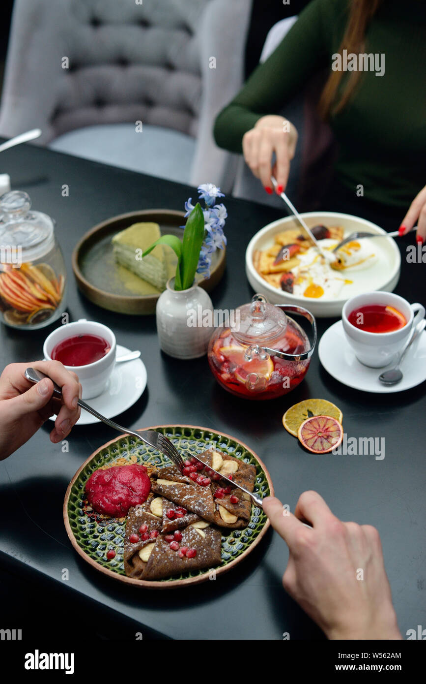 Breakfast table setting with pancakes, tea. Couple is eating Stock ...