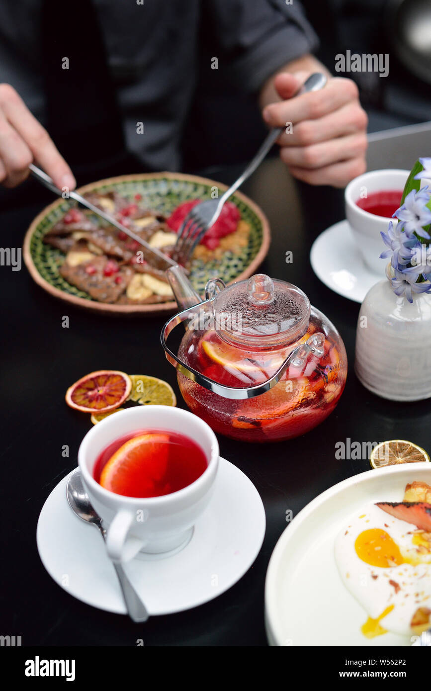 Breakfast table setting with pancakes, tea. Couple is eating Stock ...