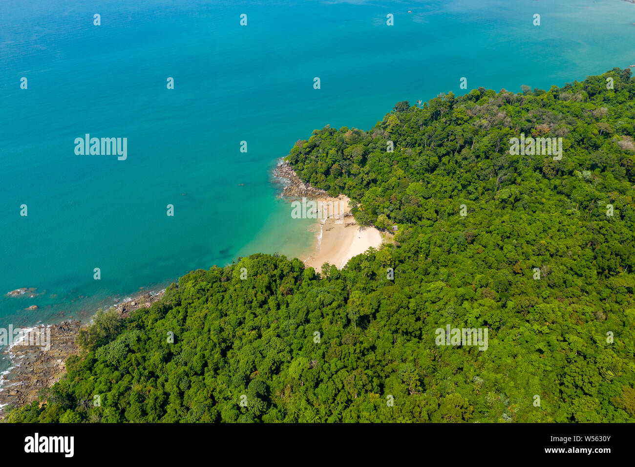 Aerial drone view of a beautiful small sandy beach surrounded by lush ...
