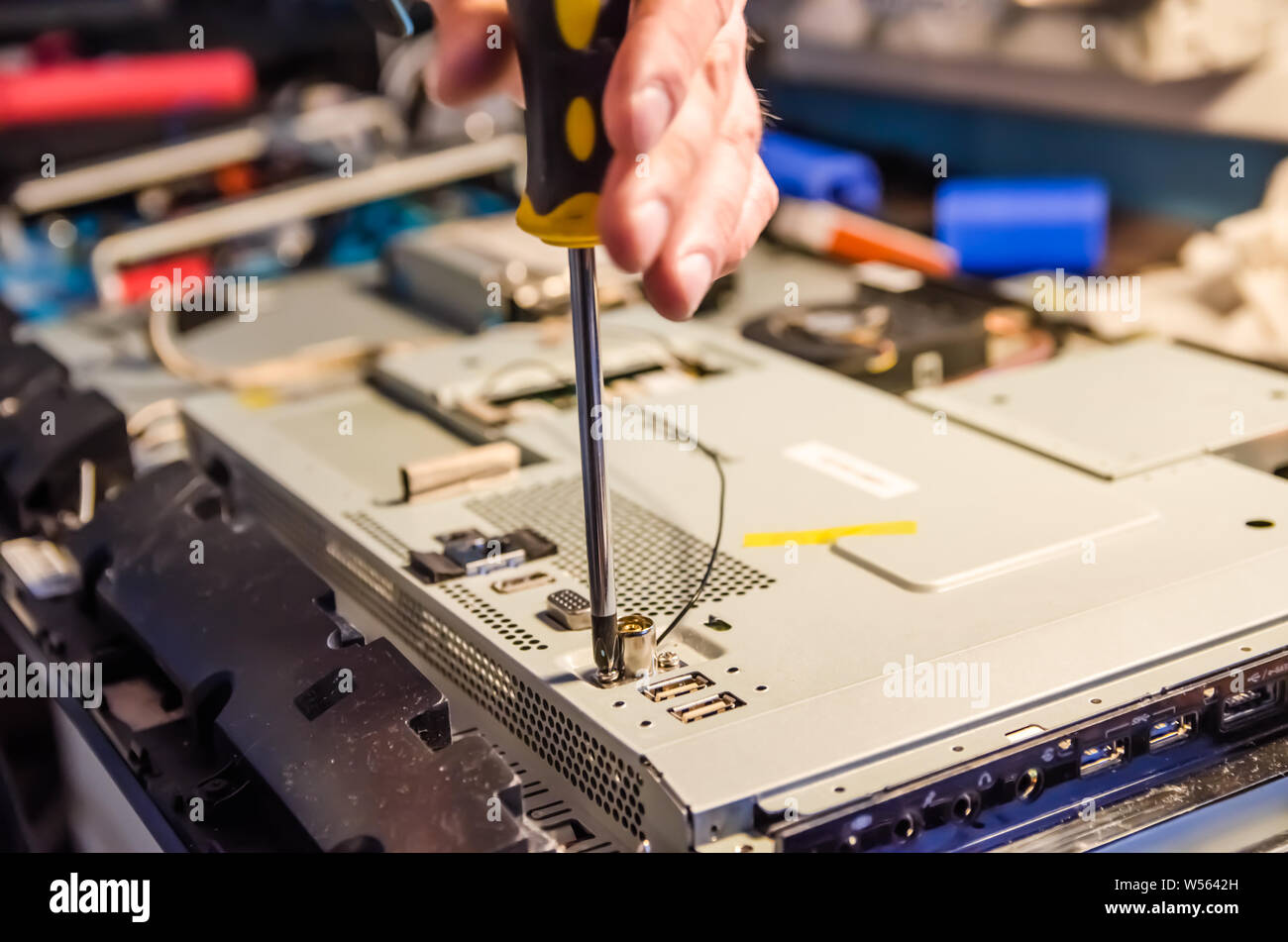 Technical support worker unspins the cover of the computer of the ...