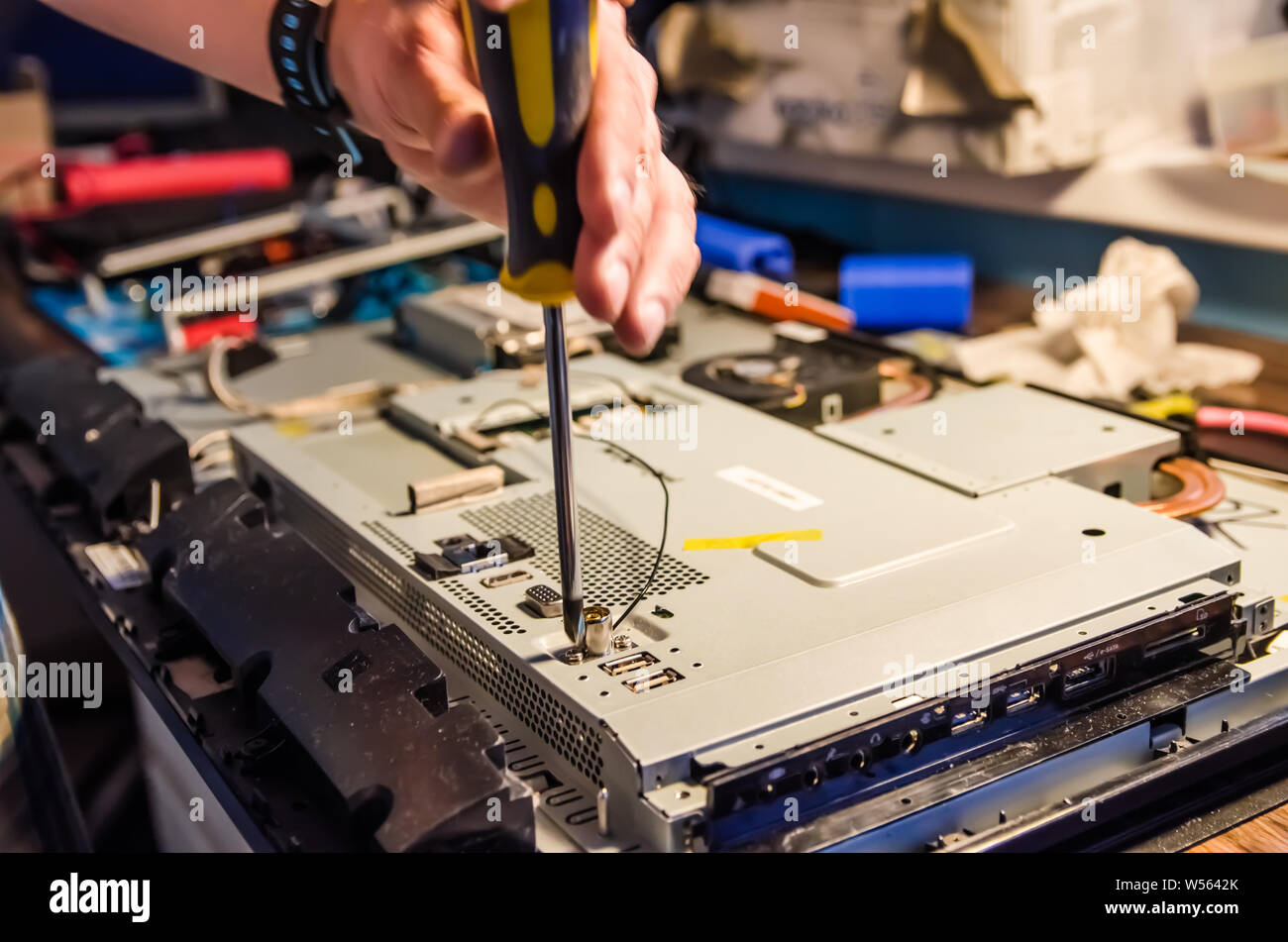 Technical support worker unspins the cover of the computer of the ...