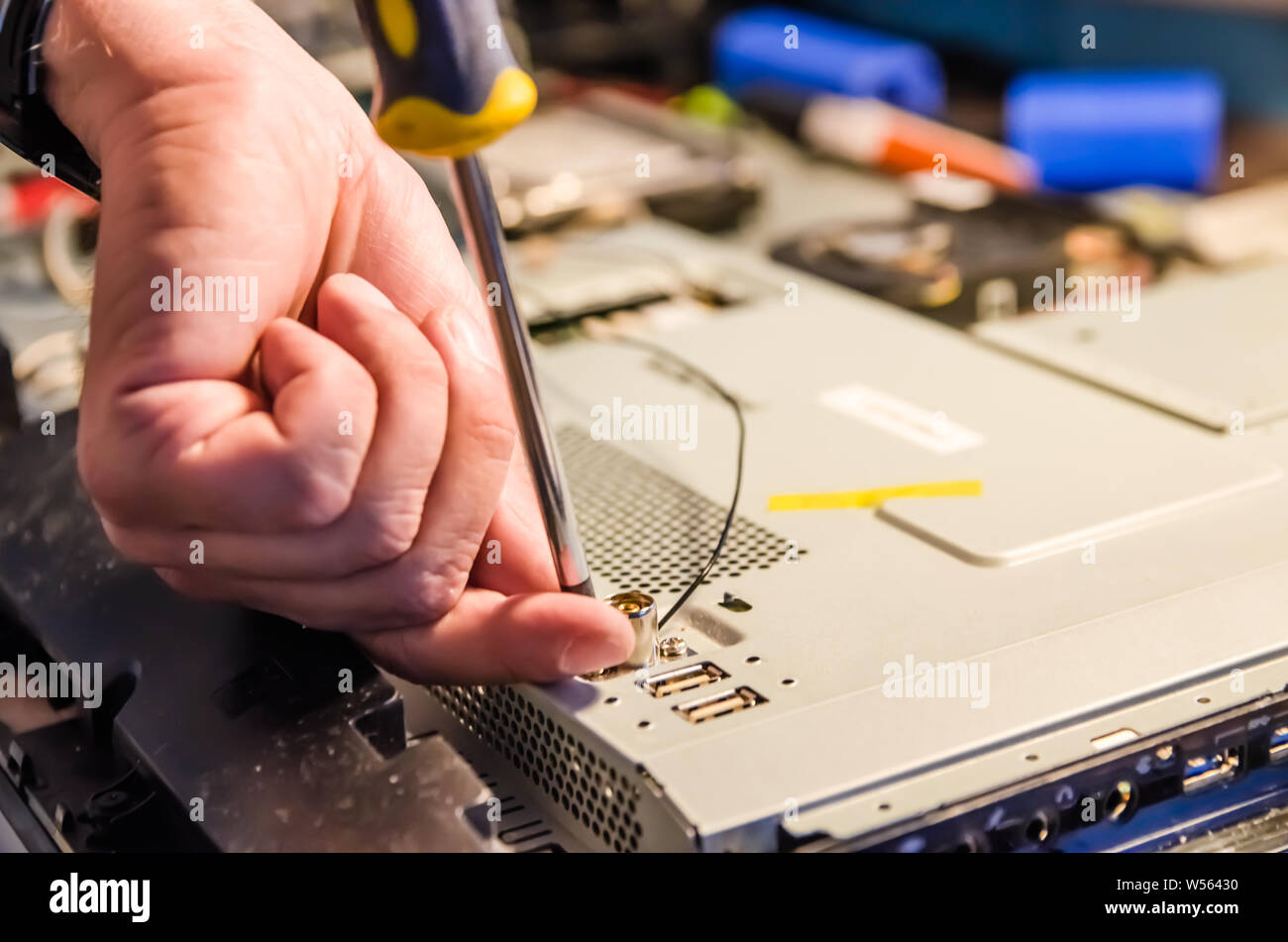 Technical support worker unspins the cover of the computer of the ...