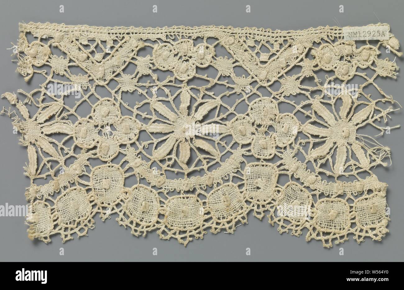 Strip of bobbin lace with flower with pointed petals and quadruple ...