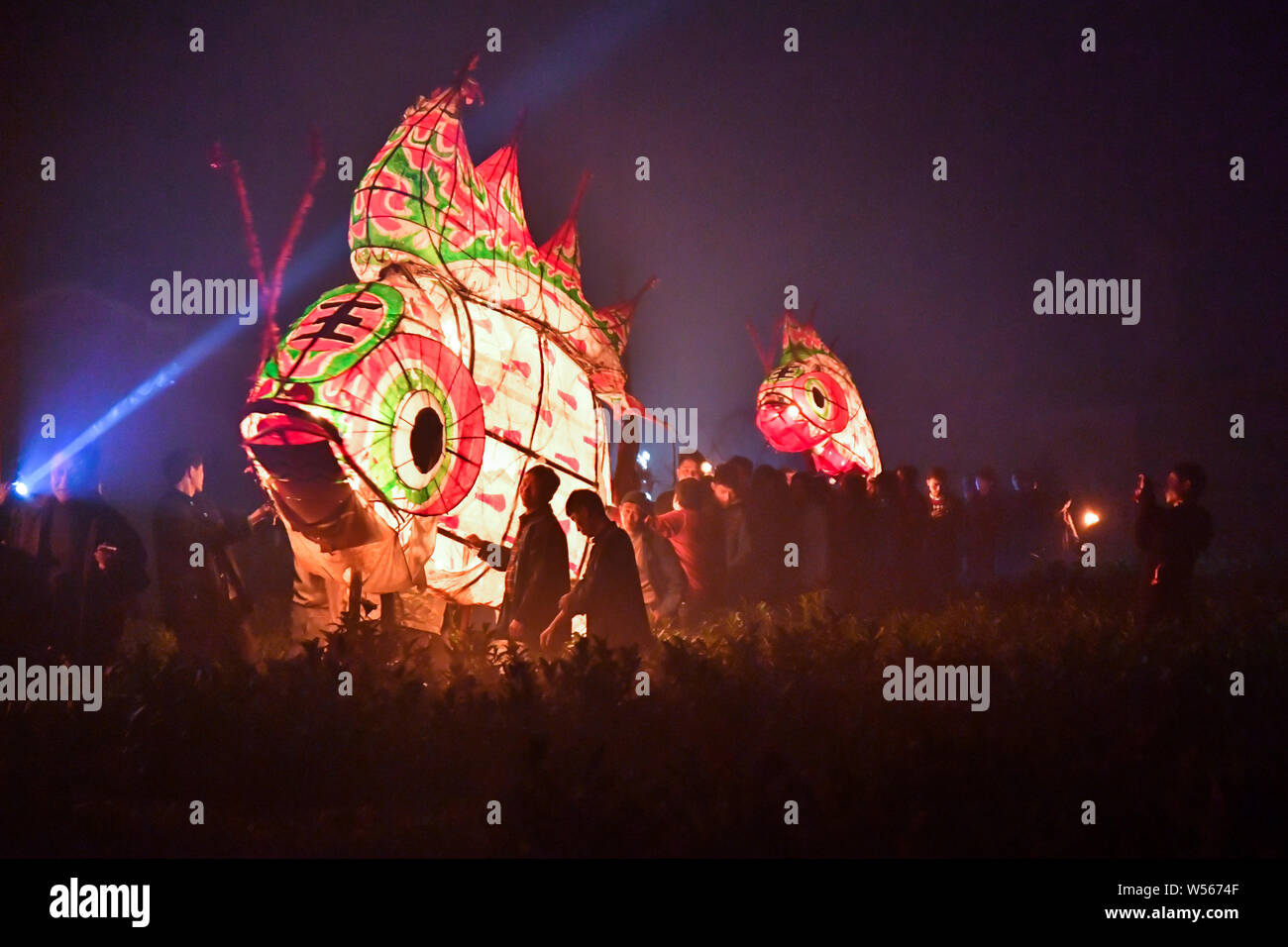 Villagers holding fish-shaped lanterns parade during a local festival ...