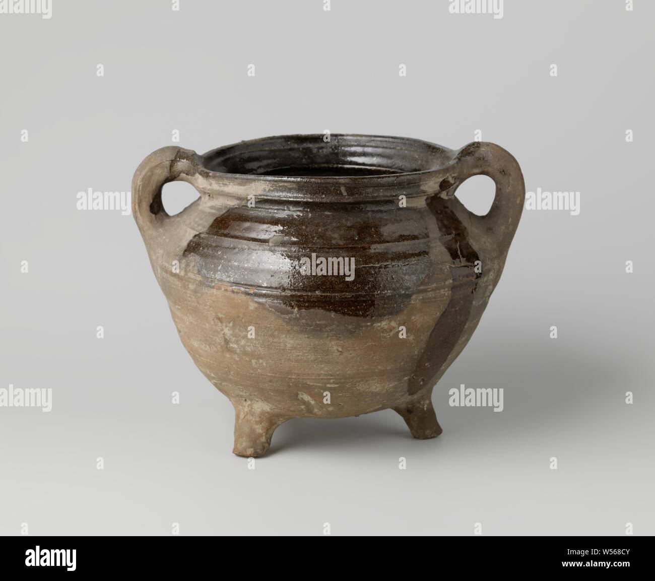 Spherical pot made of earthenware, on three legs and with two ears. The ...