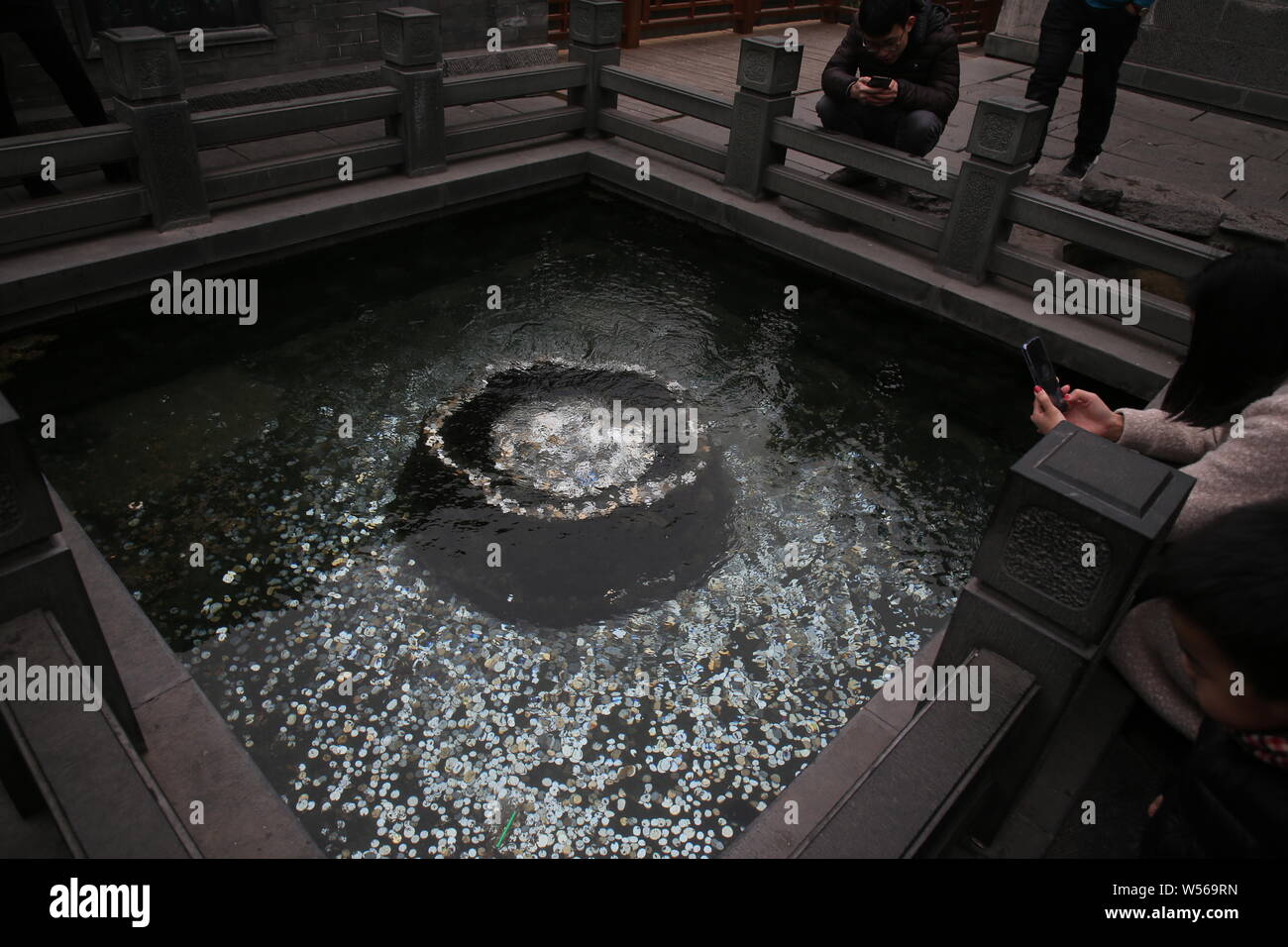 Tourists throw coins to the spring pool at the Baotu Spring Park in ...