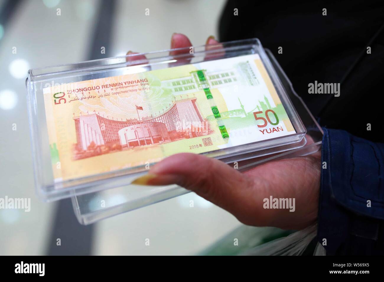 A local Chinese resident shows commemorative banknotes for the 70th ...