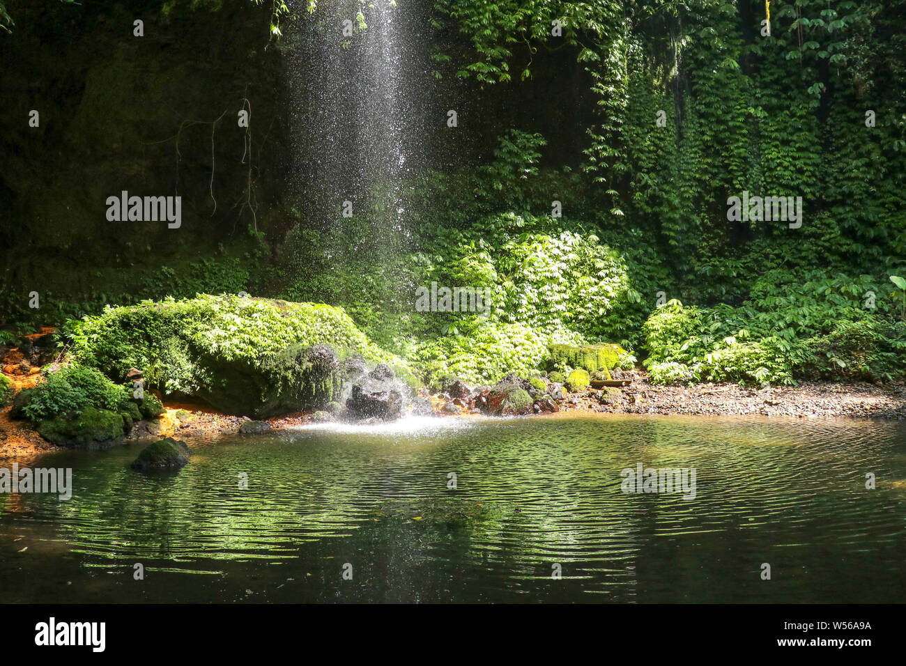 Reflection of the sun with waterfall in a small pond. Waterfall emerald ...