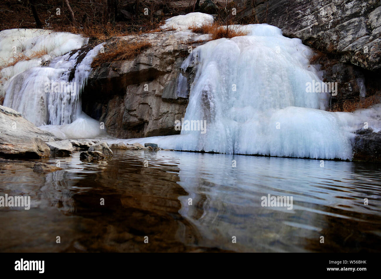 Tourists pose for photos with the icefall scenery at the Shenquan Gorge ...