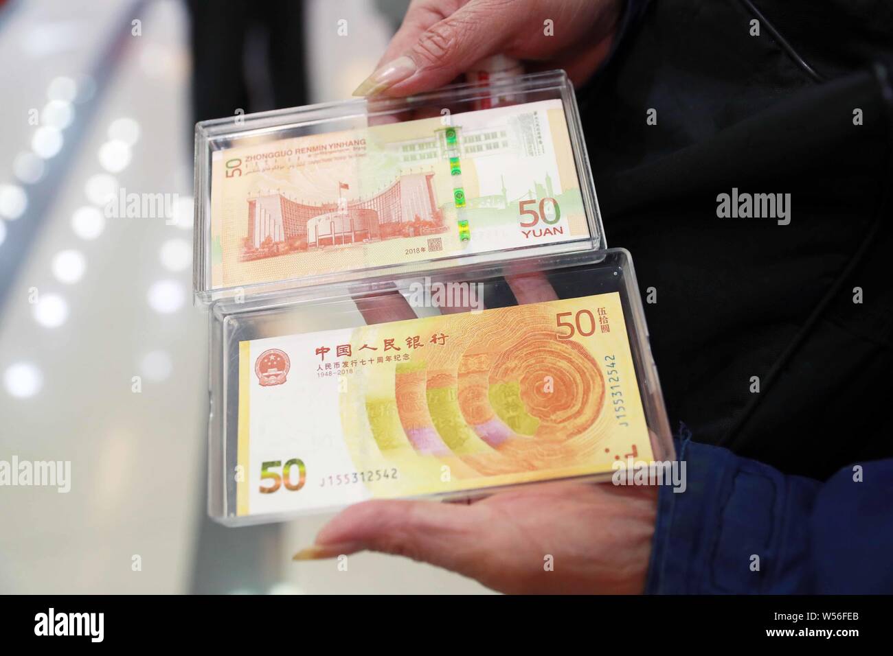 A local Chinese resident shows commemorative banknotes for the 70th ...