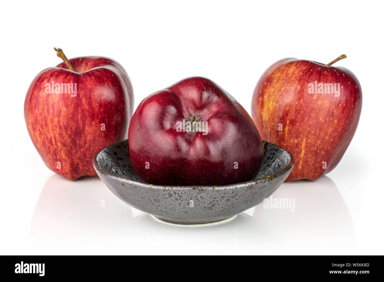 Group of three whole fresh apple red delicious in a dark ceramic bowl ...