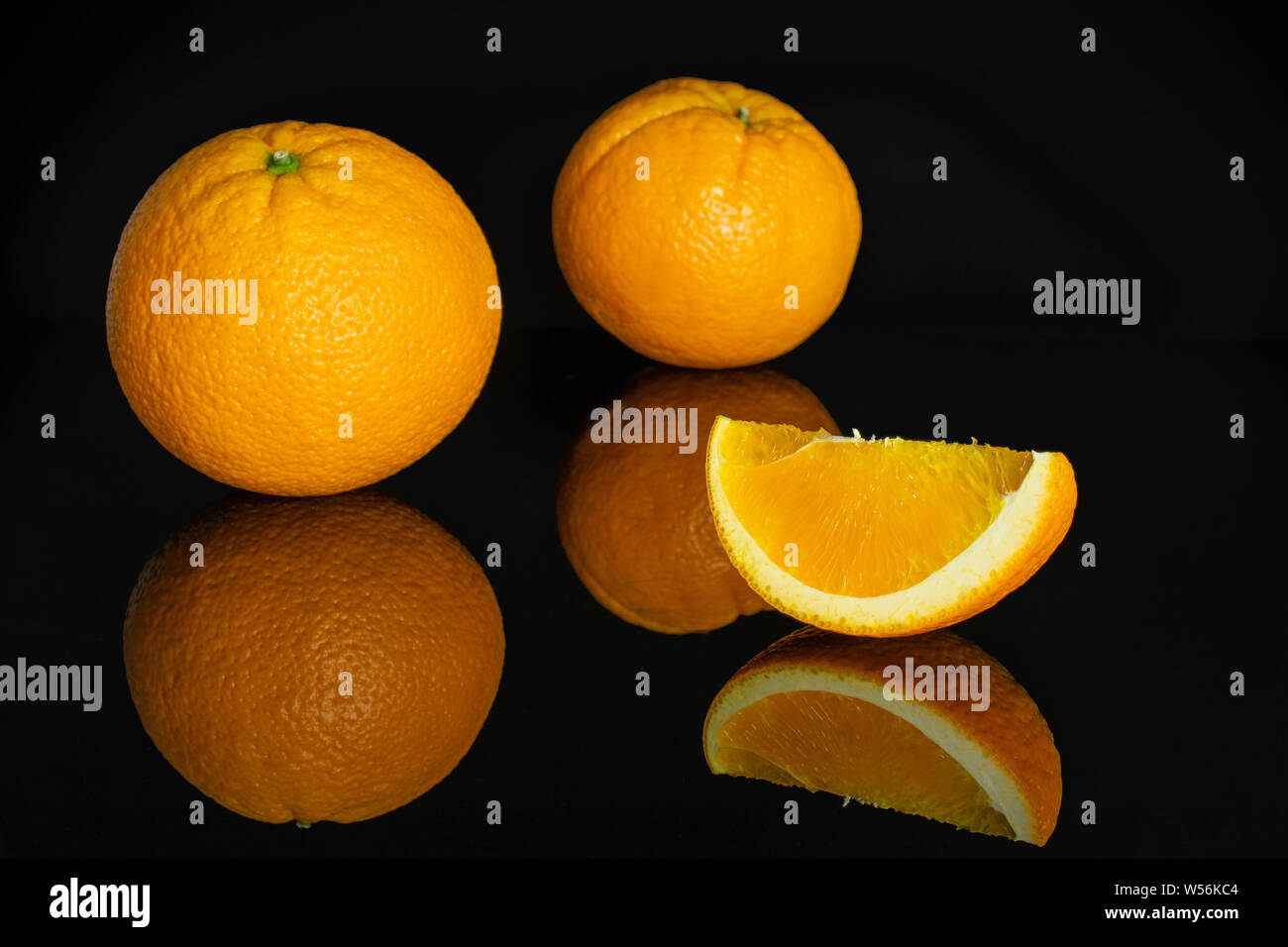 Group of two whole one slice of fresh sweet orange isolated on black ...