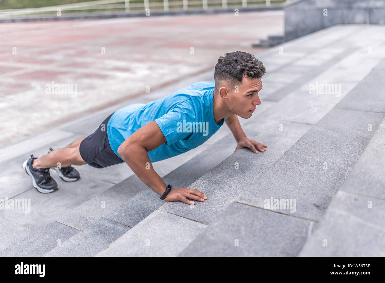 young guy, a male athlete, is wrung out in summer city, training ...