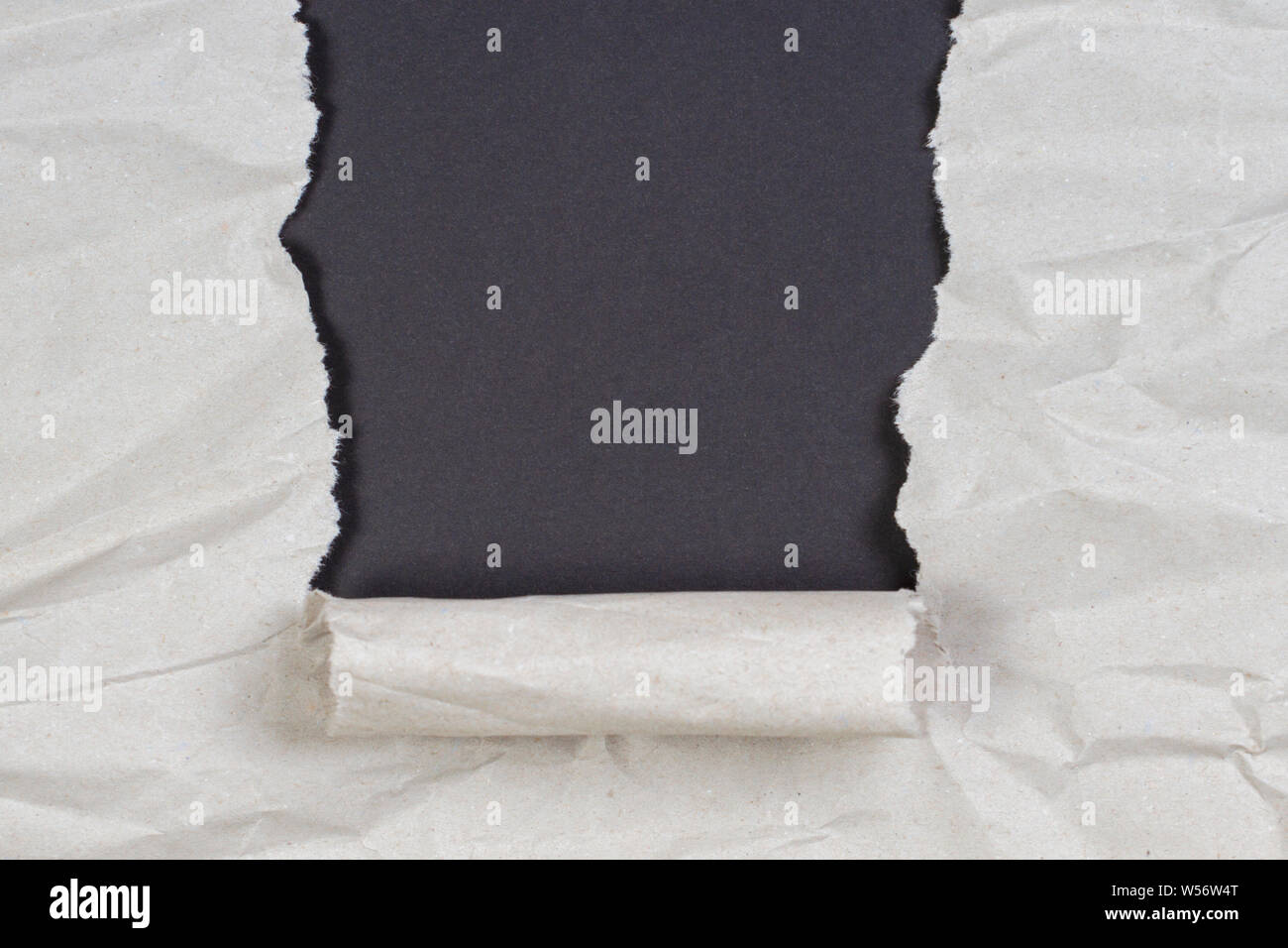 Crumpled package paper torn to reveal black background with copy space ...