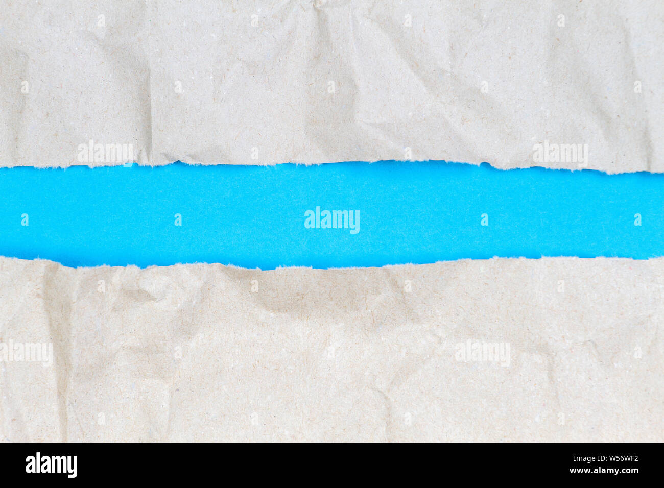 Brown package paper torn to reveal blue background with copy space ...