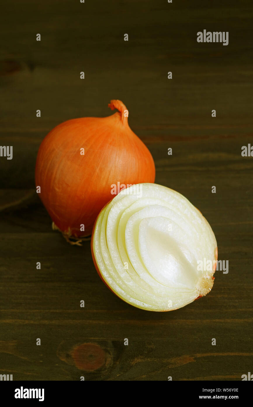 Vertical image of a whole onion and a cut in half isolated on dark ...