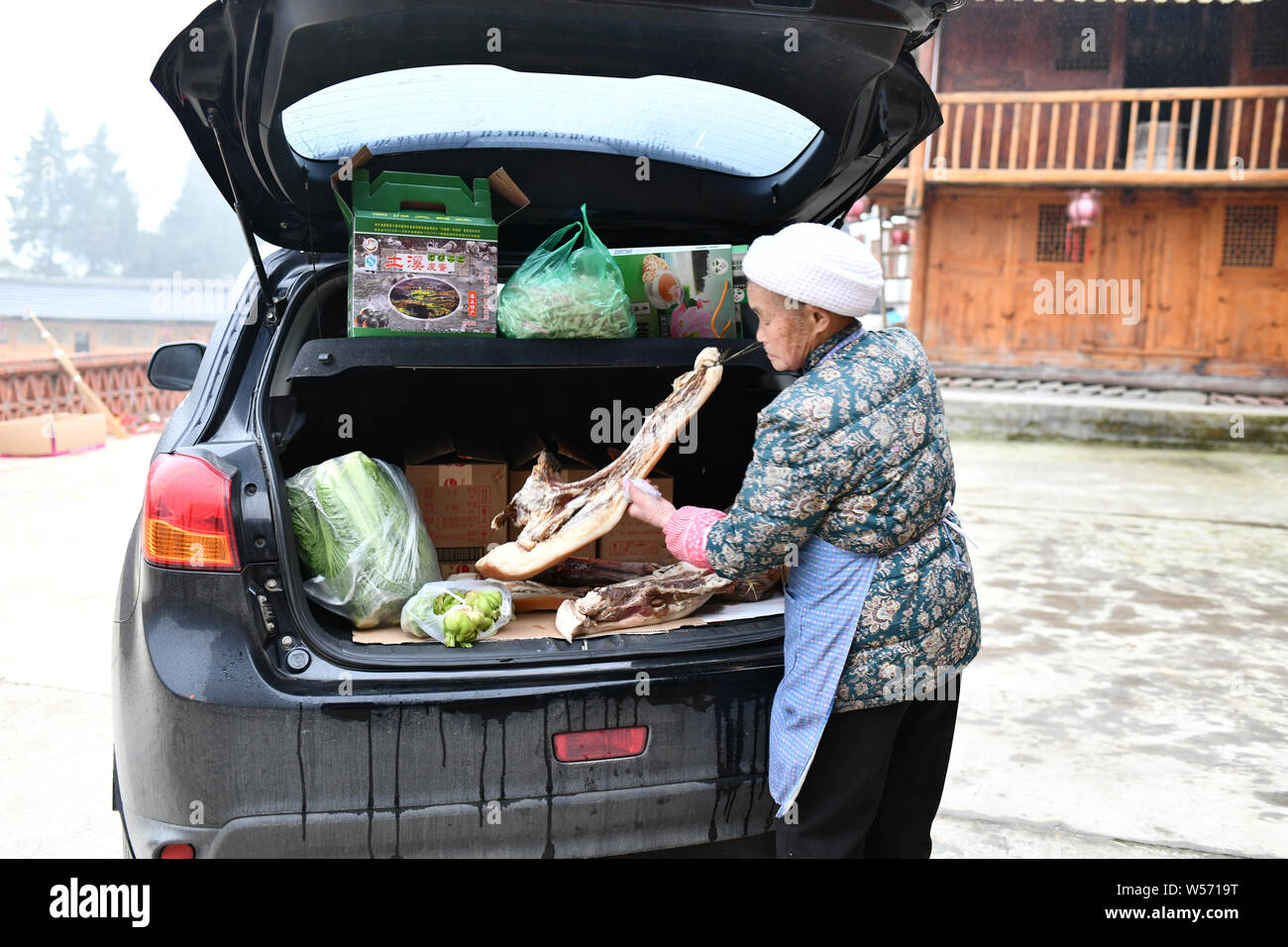 A Chinese woman prepares local items and loads to the back of her son's ...