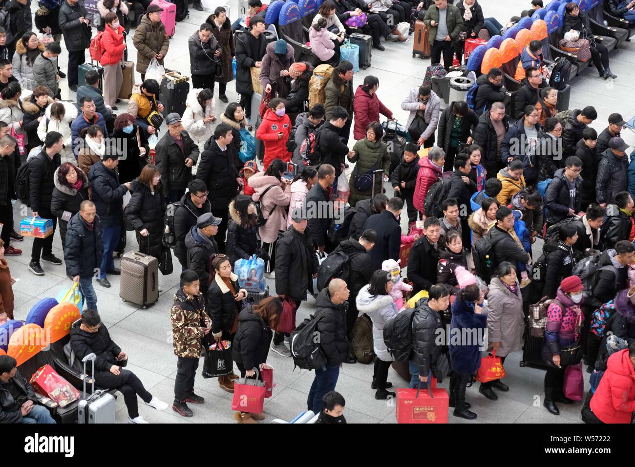 Passengers queue up to have their train tickets scanned for check-in ...