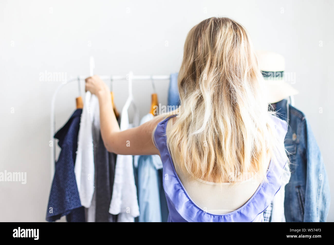 Blondy girl near a wardrobe with clothes can not choose what to wear ...
